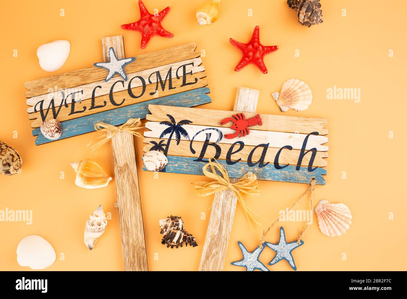 Wooden signs welcome beach, starfish and shells on yellow background ...