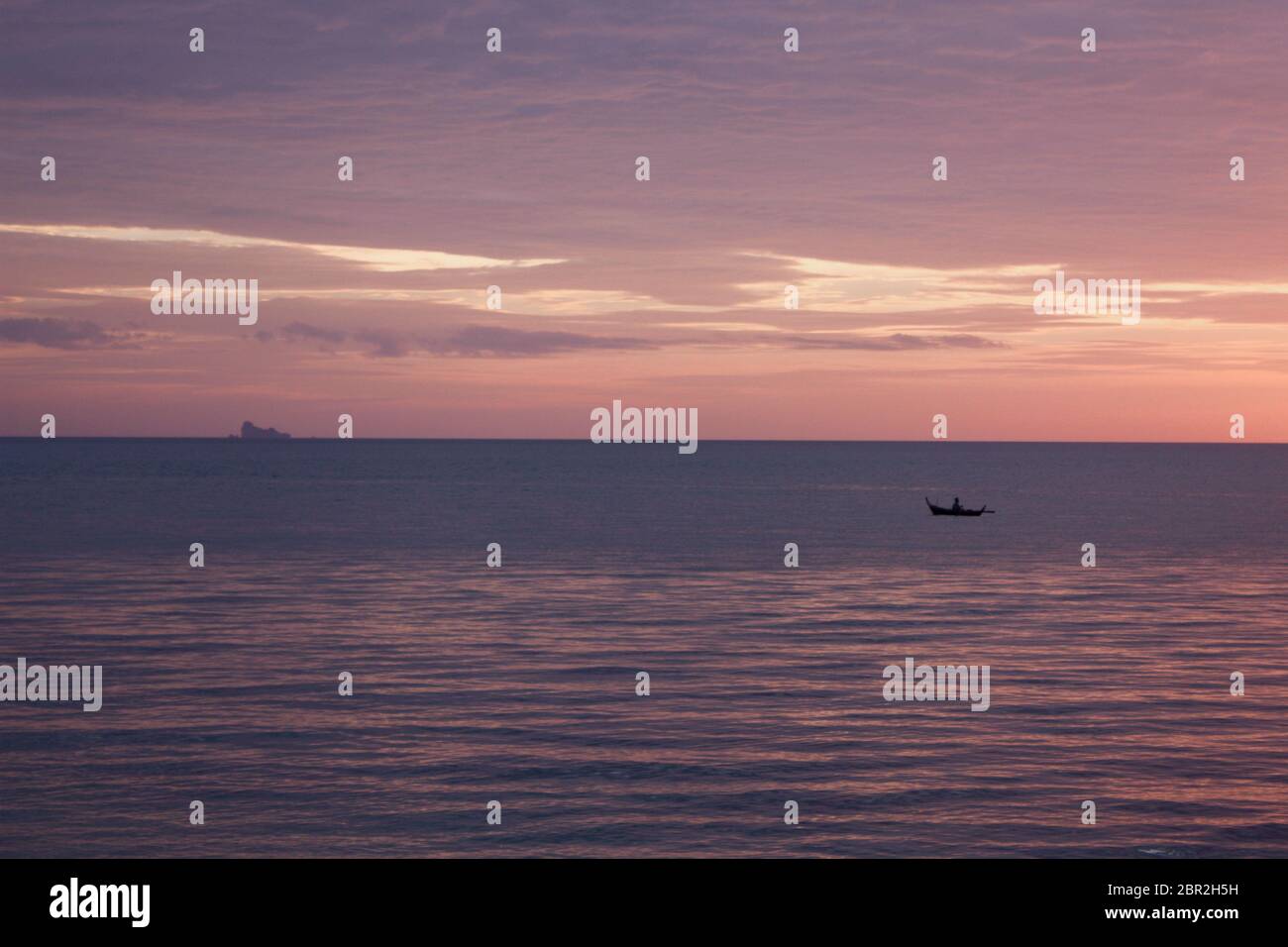 An islander paddles a dug out canoe in Thailand at sunset Stock Photo ...