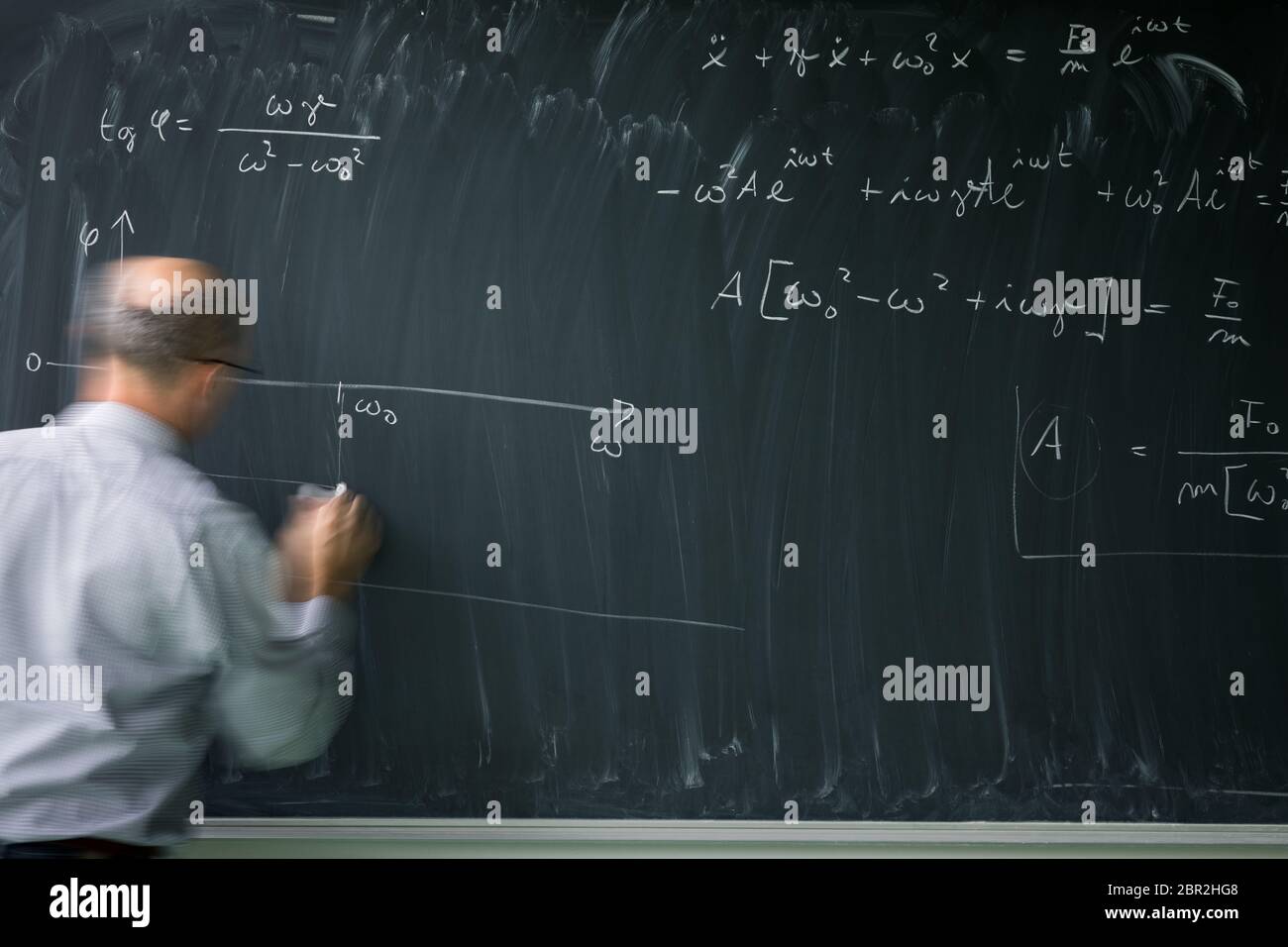 Math teacher drawing fuction graph on a blackboard during mathclass ...