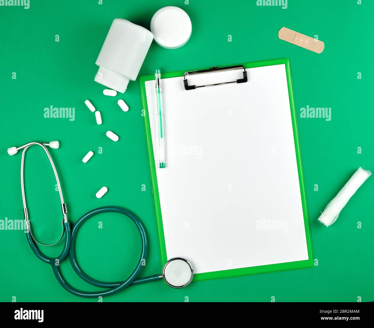 paper holder with empty white sheets, medical stethoscope, pills on a ...