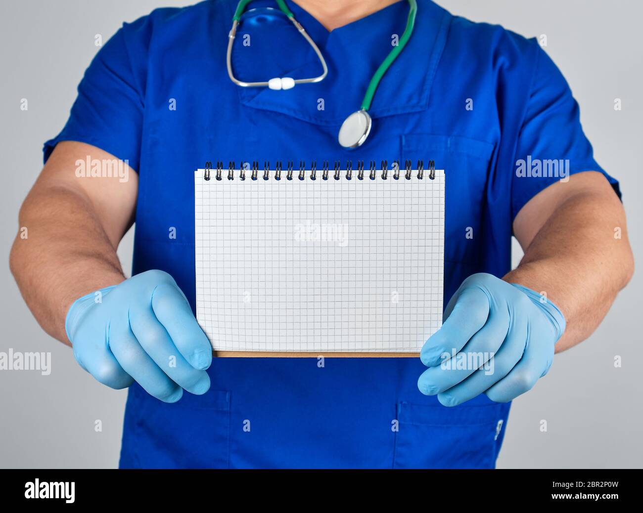 doctor in blue uniform and sterile latex gloves holding open blank ...