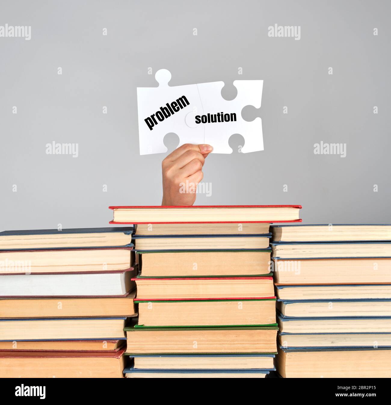 female hands holding big white puzzles over a stack of books, gray ...