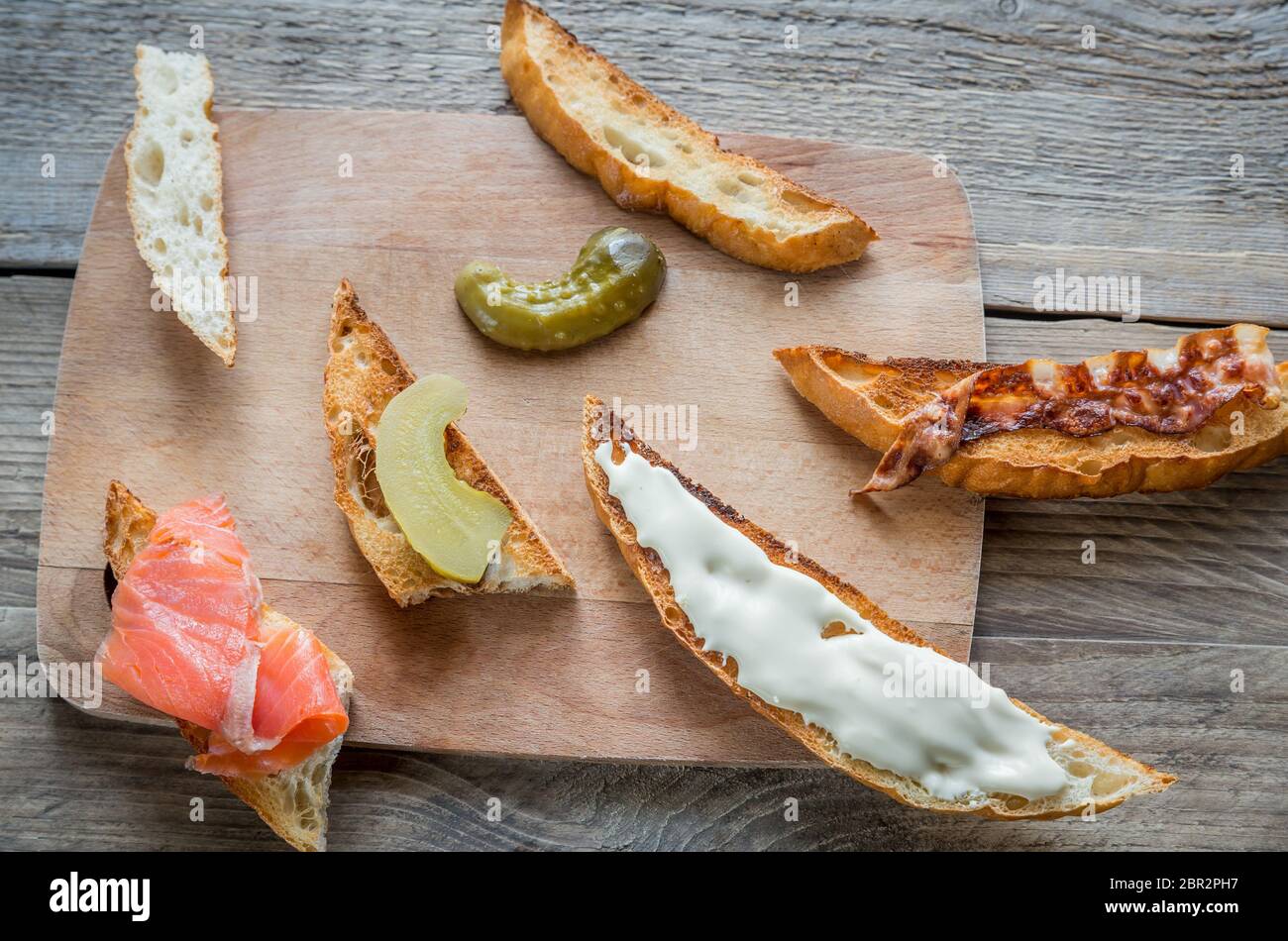 Toasts with different toppings on the wooden board Stock Photo - Alamy