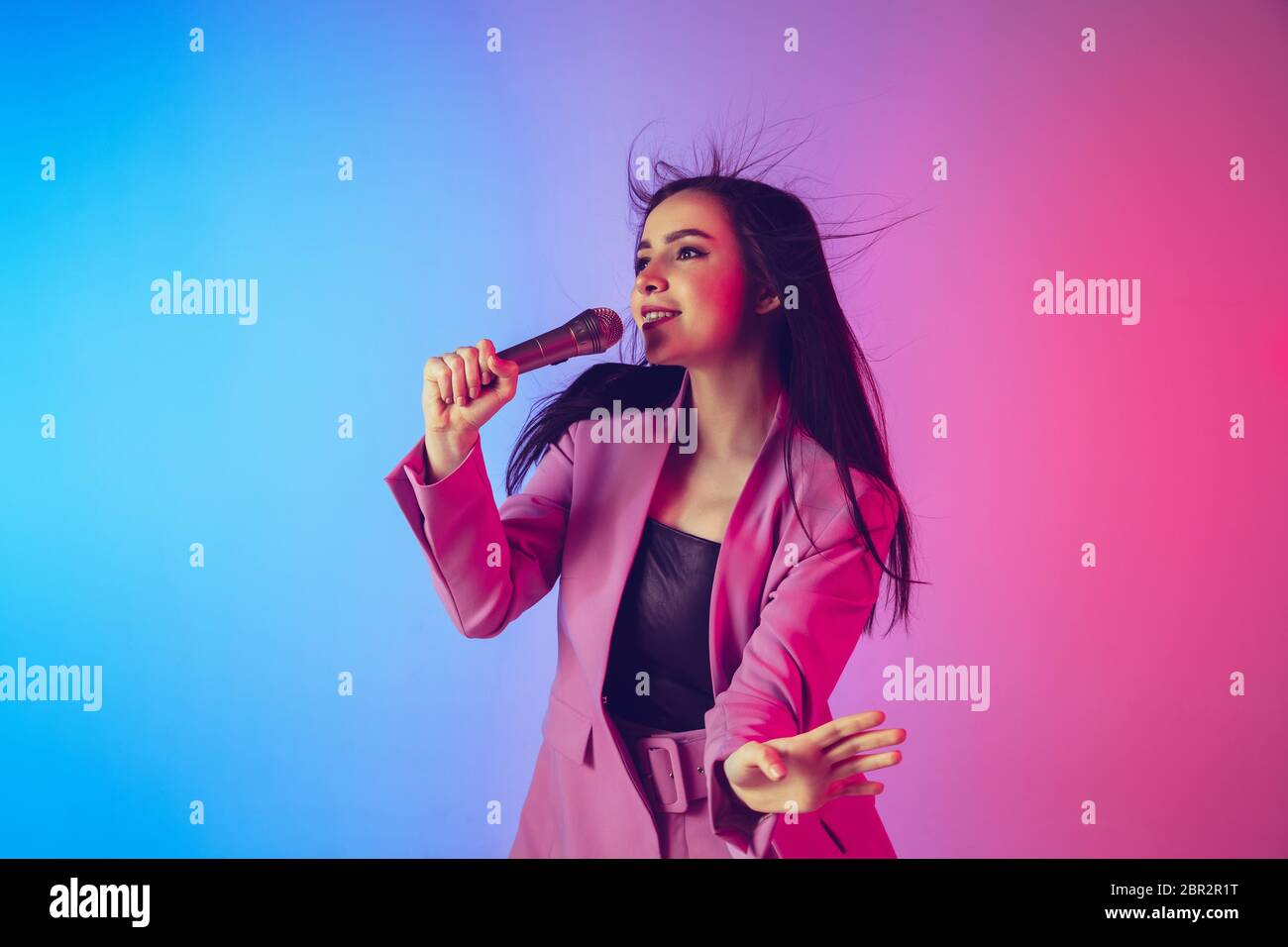 Caucasian female singer portrait isolated on gradient studio background ...