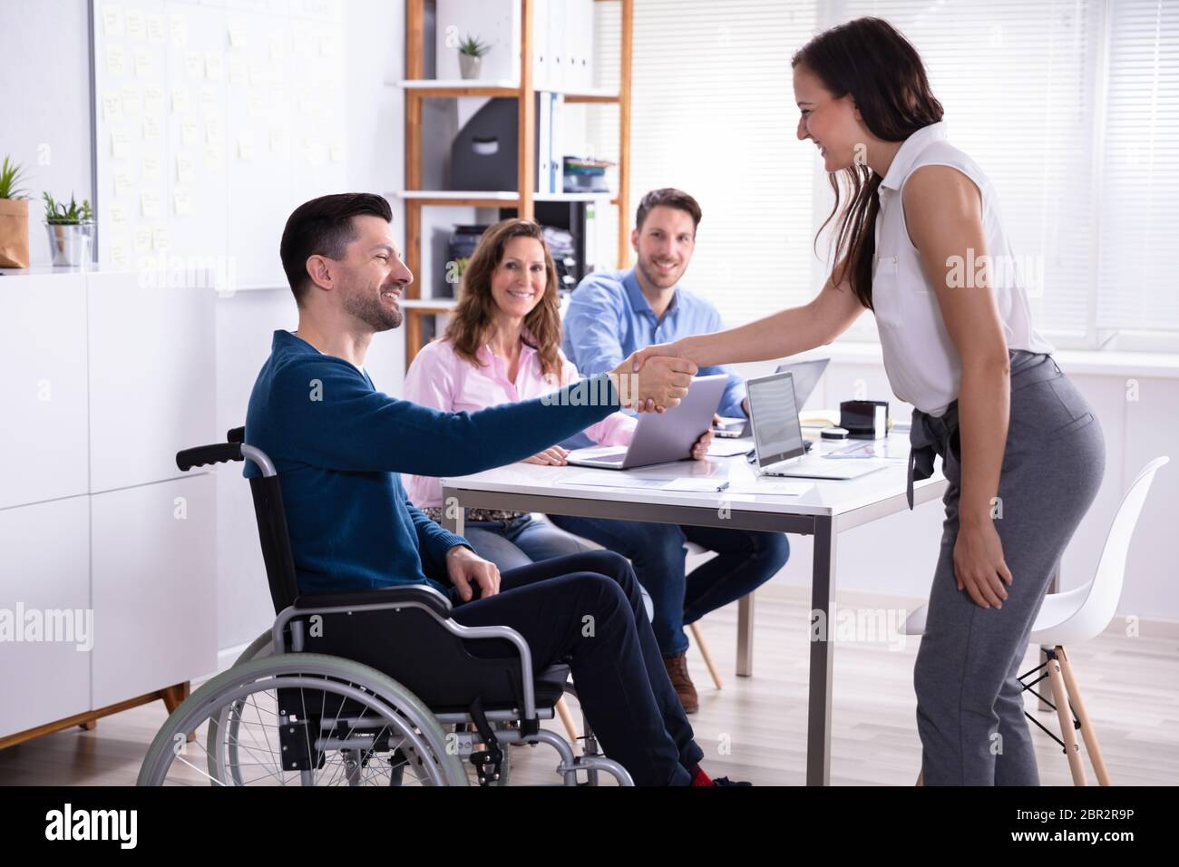 Disabled Happy Businessman Shaking Hand With His Female Colleague In ...