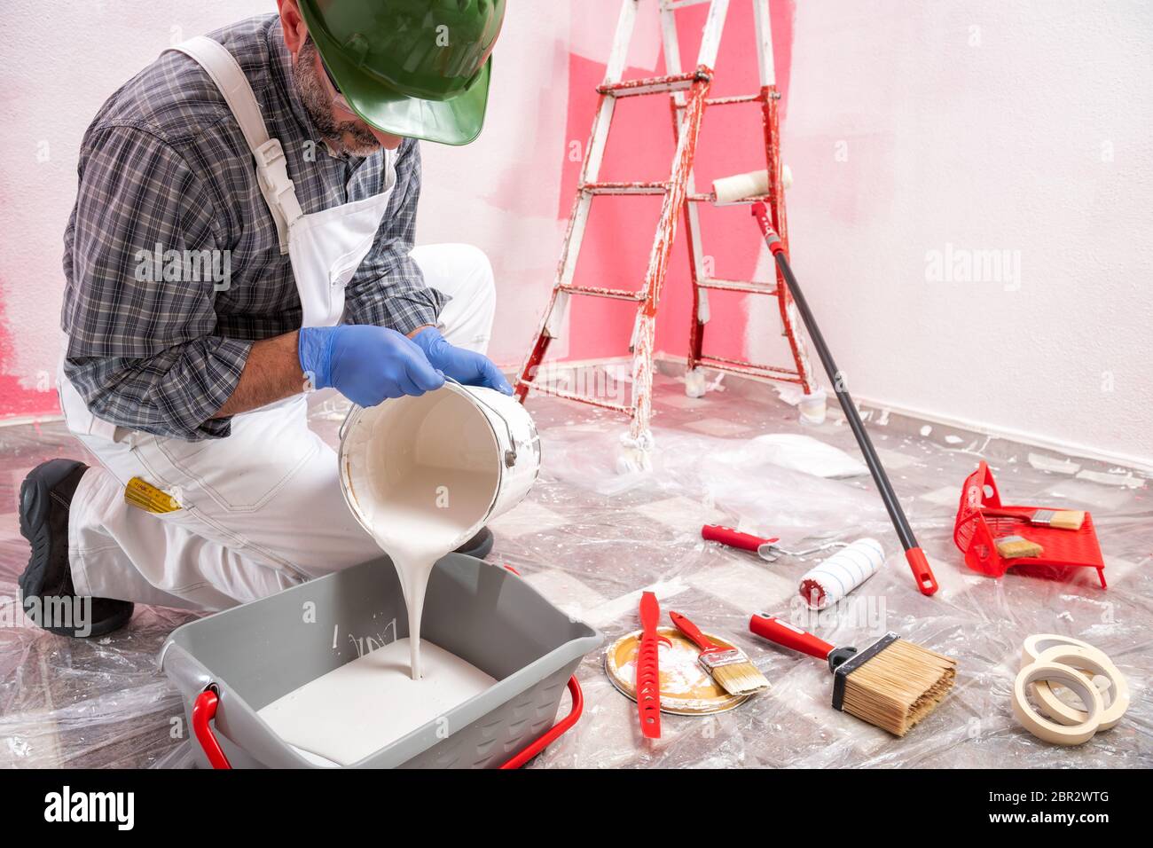 Caucasian house painter worker in white overalls, with helmet and ...