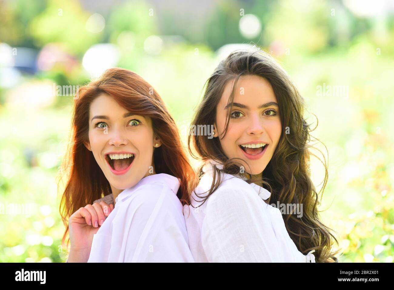 Two excited women friends girls posing on green nature background ...