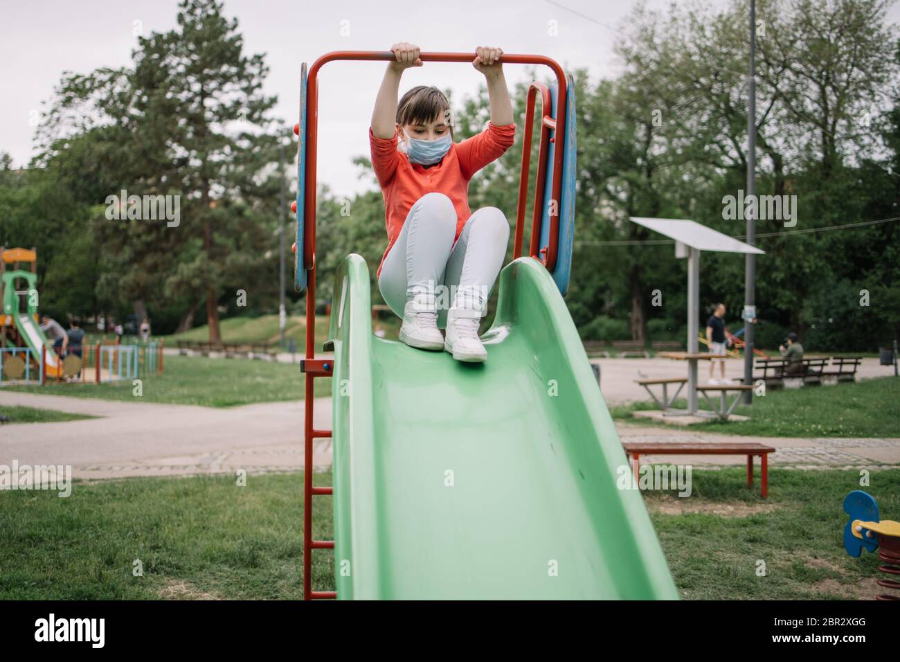 Front view of young girl with protection mask on her face going down a ...