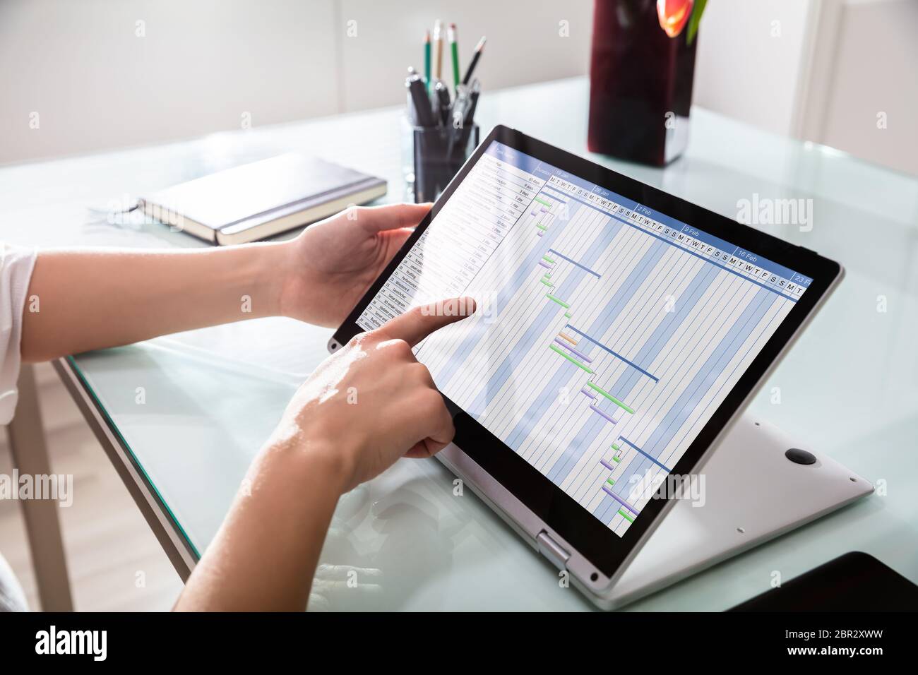Businessperson's Hand Analyzing Gantt Chart On Laptop Over Reflective ...
