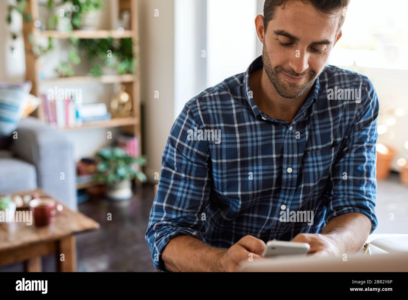 Young man reading a text message while working from home Stock Photo ...