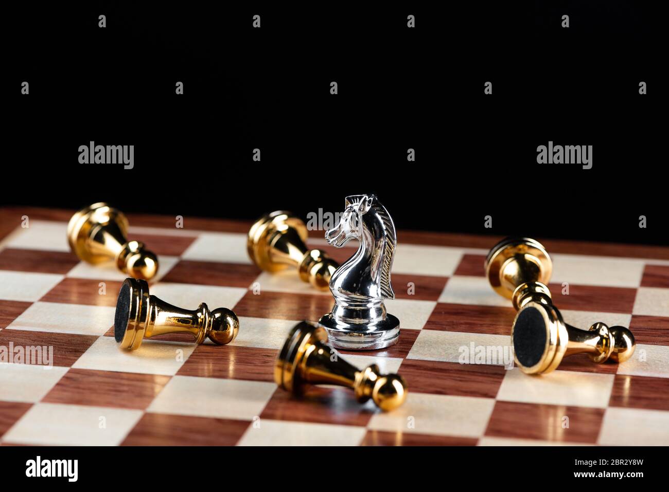 Silver knight chess defeats gold pawns on board Stock Photo - Alamy