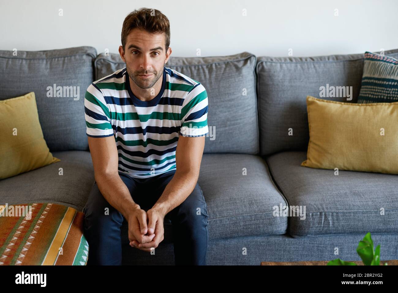 Young man sitting alone on his living room sofa Stock Photo - Alamy