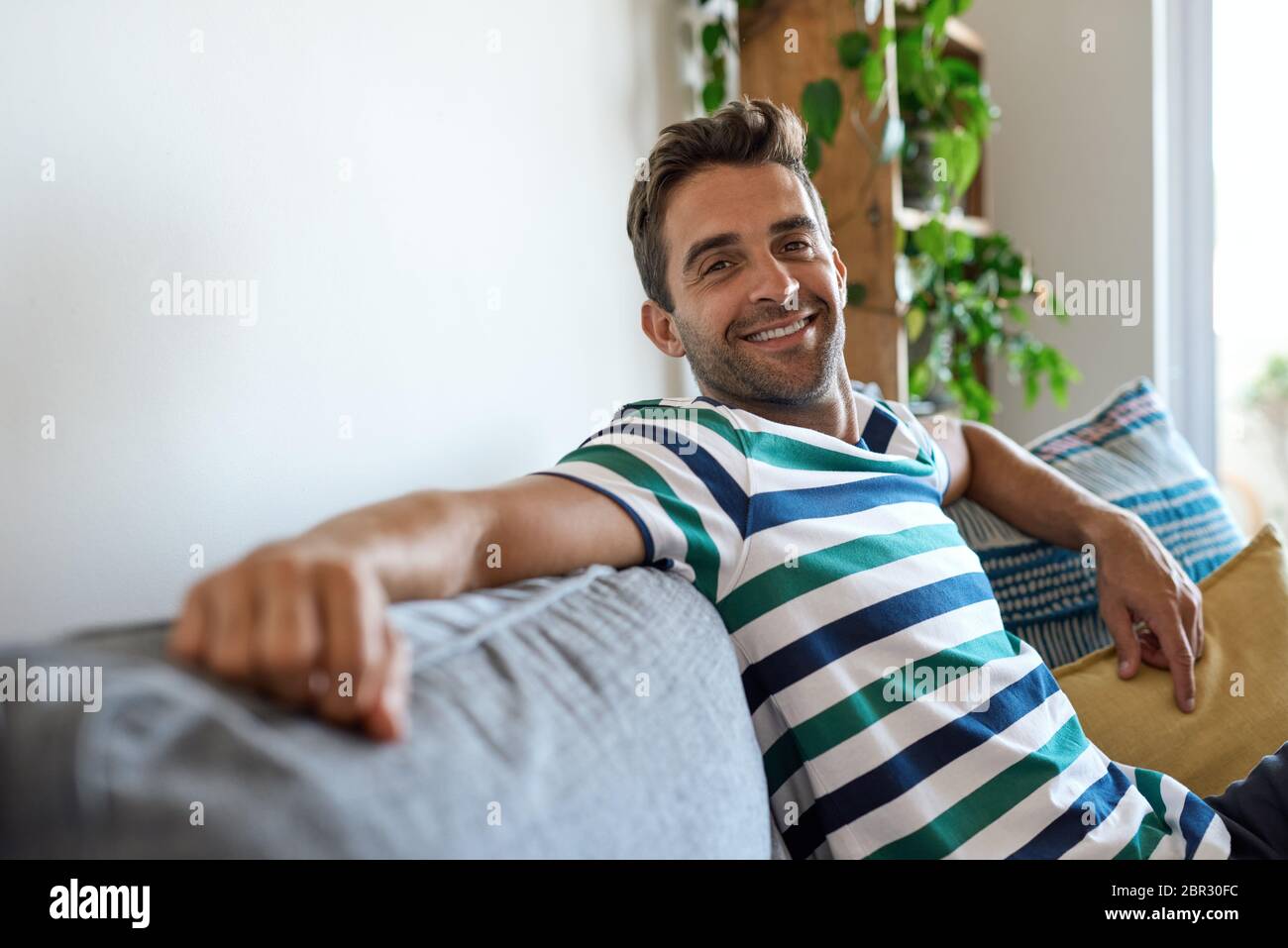 Smiling young man sitting on hi-res stock photography and images - Alamy