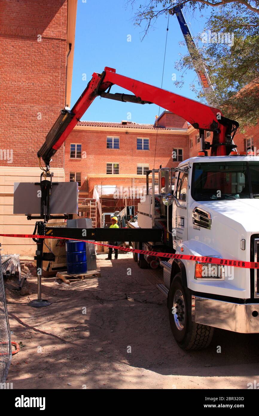 A delivery truck hoisting a heavy load into a building site at the ...