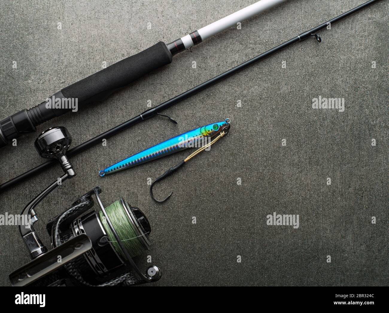 Fishing gear with rod and reel with line ready for jigging on gray ...