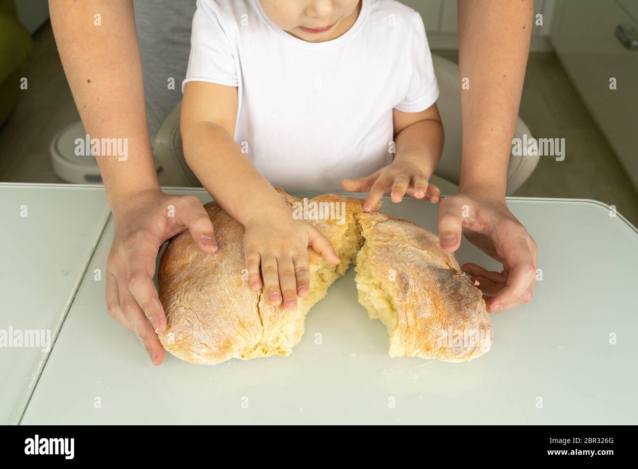 dad and child are breaking freshly baked white bread. family values ...