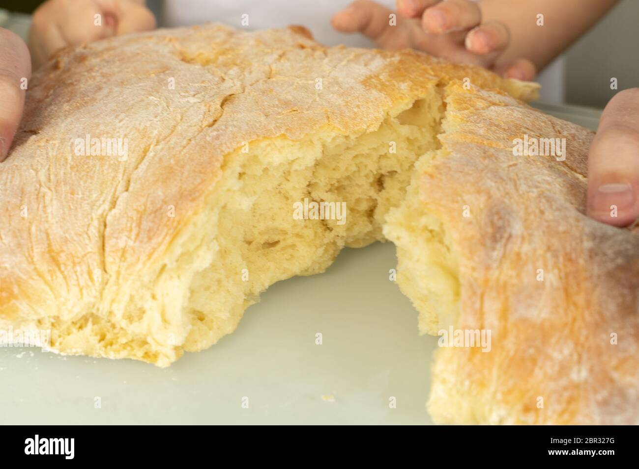 freshly baked white bread is broken, in the background children Stock ...