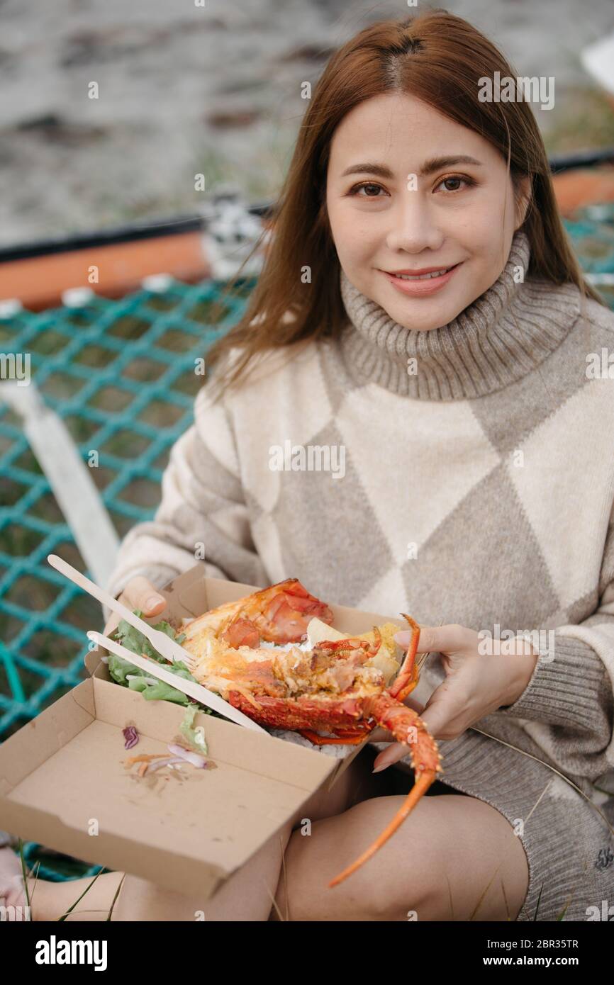 Beautiful asian woman holding a lobster claw or crayfish outdoor with ...