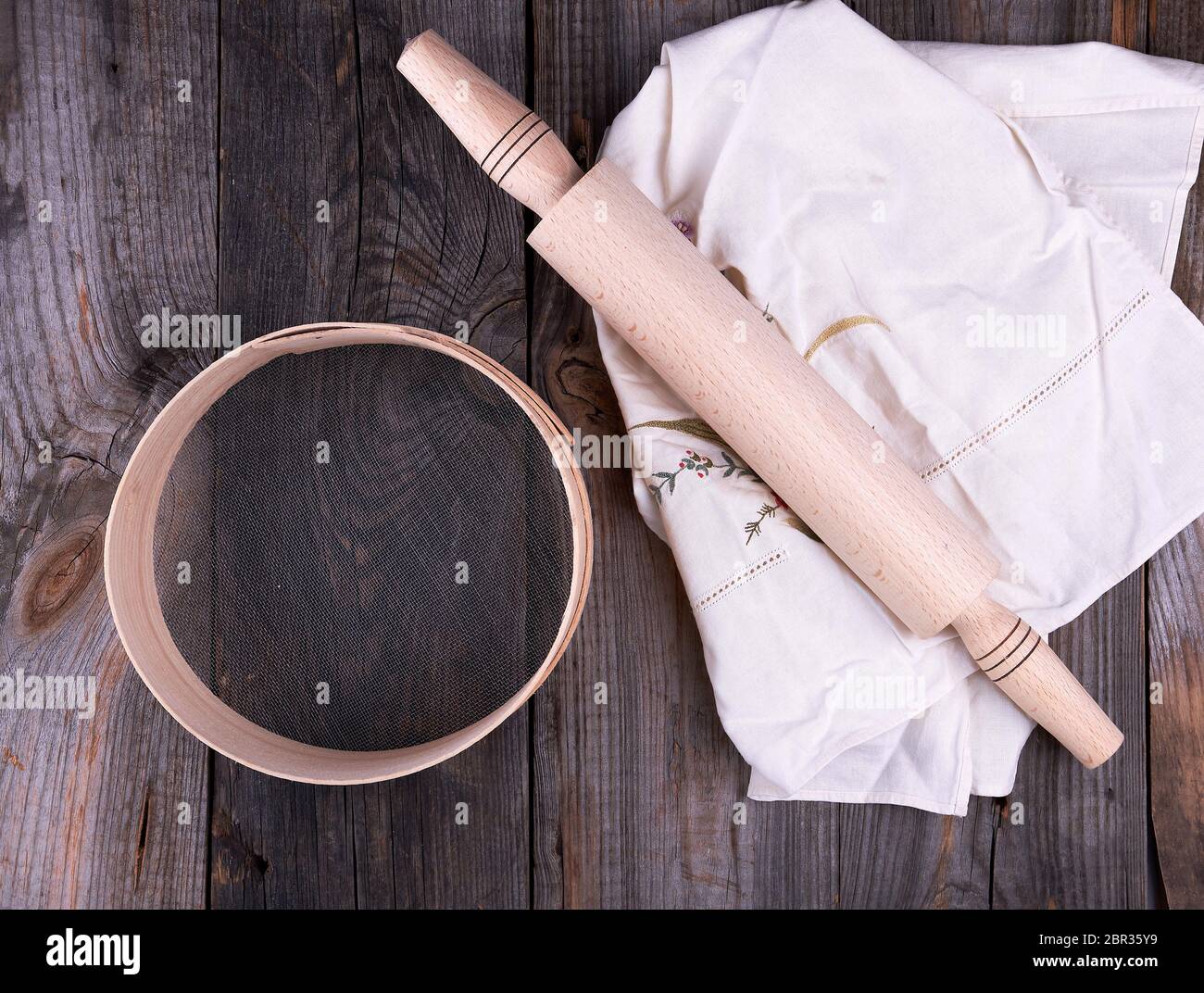 new wooden rolling pin on a textile napkin with embroidery and a round ...