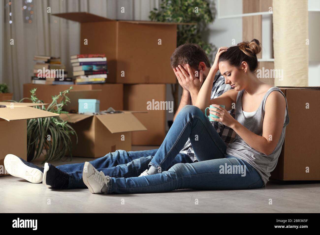 Sad evicted couple moving home complaining sitting on the floor in the ...