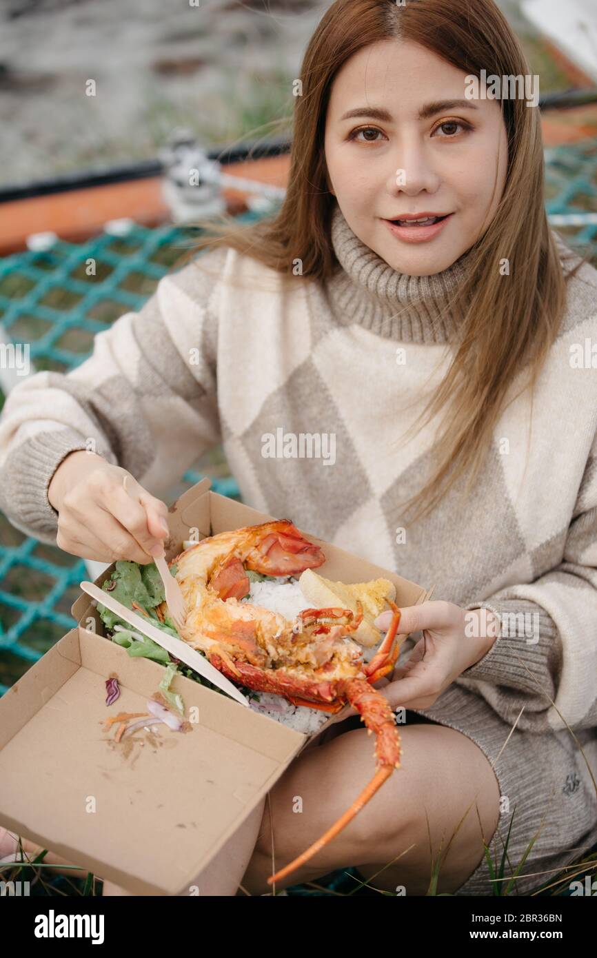 Beautiful asian woman holding a lobster claw or crayfish outdoor with ...