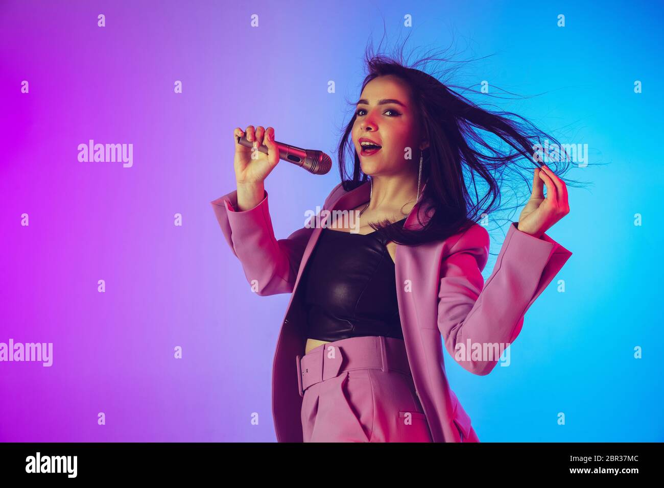 Caucasian female singer portrait isolated on gradient studio background ...