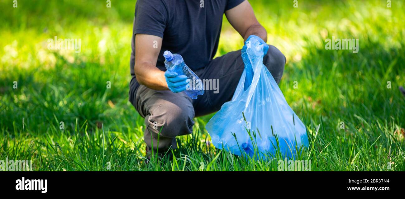 Man picking up plastic bottle, garbage collecting in a forest cleaning ...