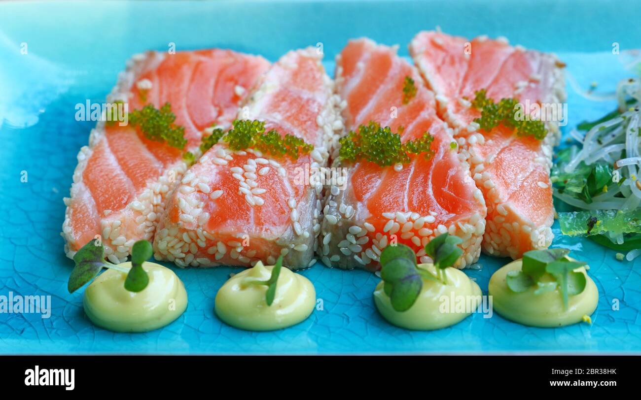 Close up portion of fresh raw salmon fish sashimi with sesame seeds ...