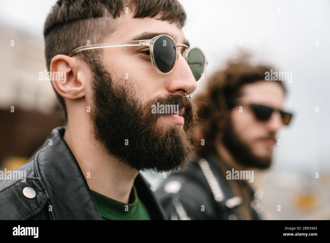 Photo closeup of bearded caucasian men bikers in sunglasses posing and looking forward together ...
