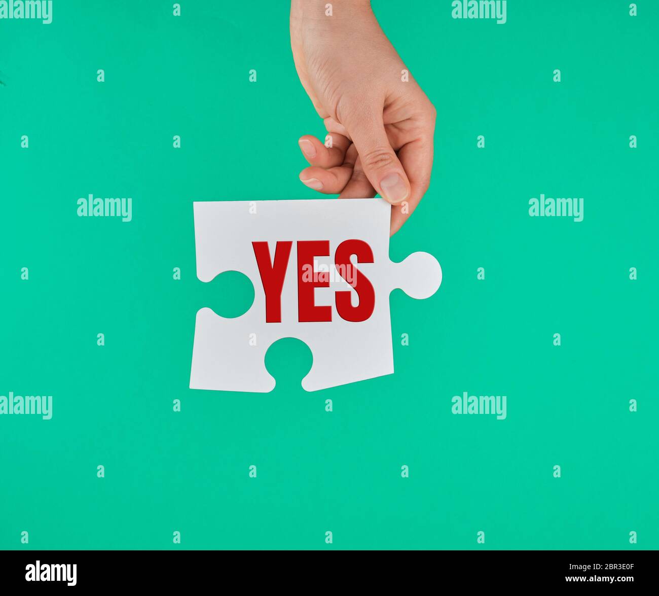 big white puzzle in hand on a green background, the inscription is yes ...