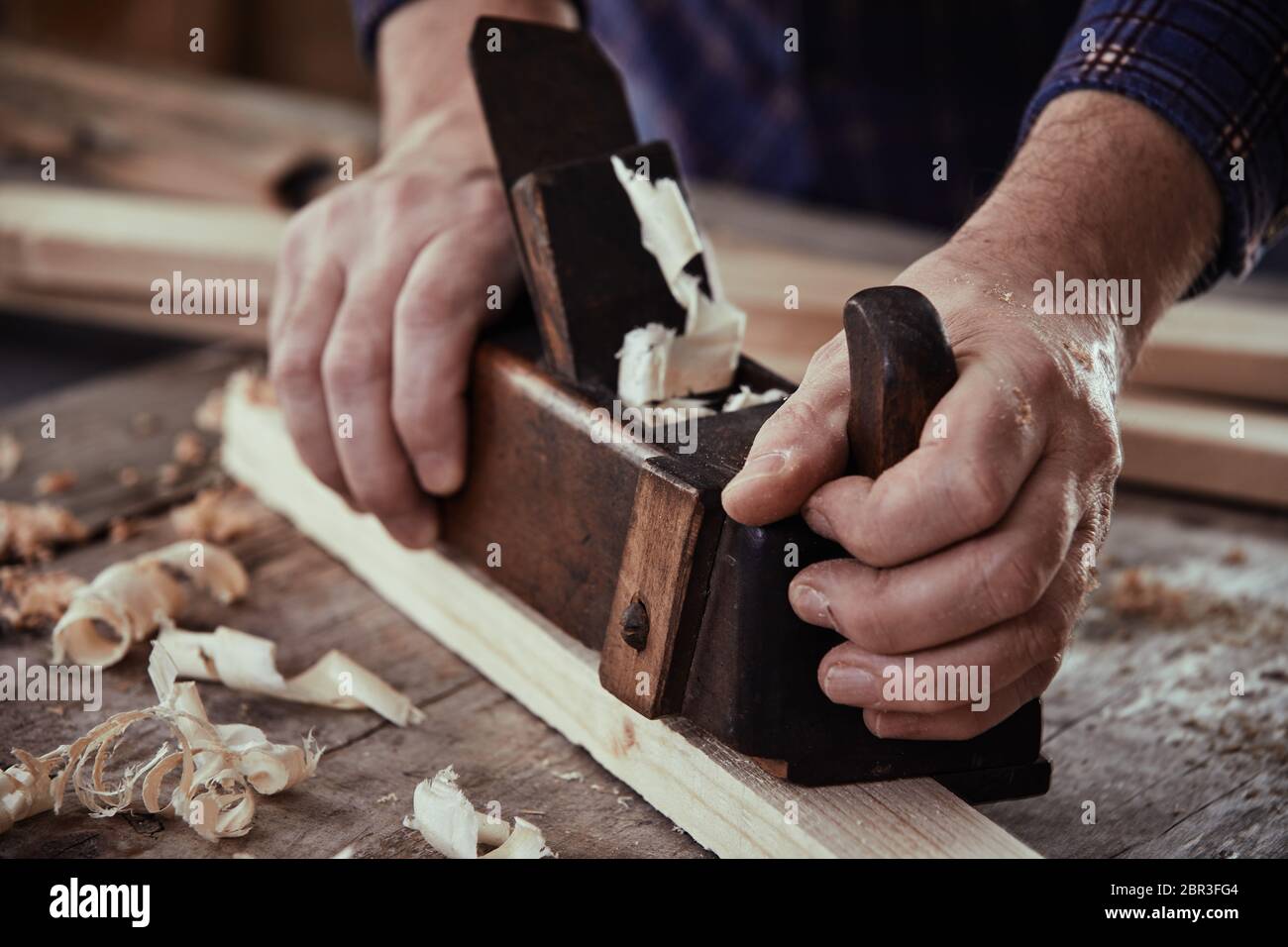 Hands of a carpenter, woodworker or joiner using a vintage plane to ...