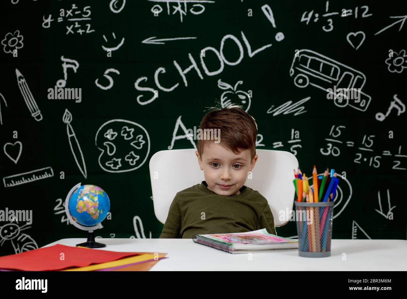 Cute child boy doing homework. Clever kid drawing at desk. Schoolboy ...