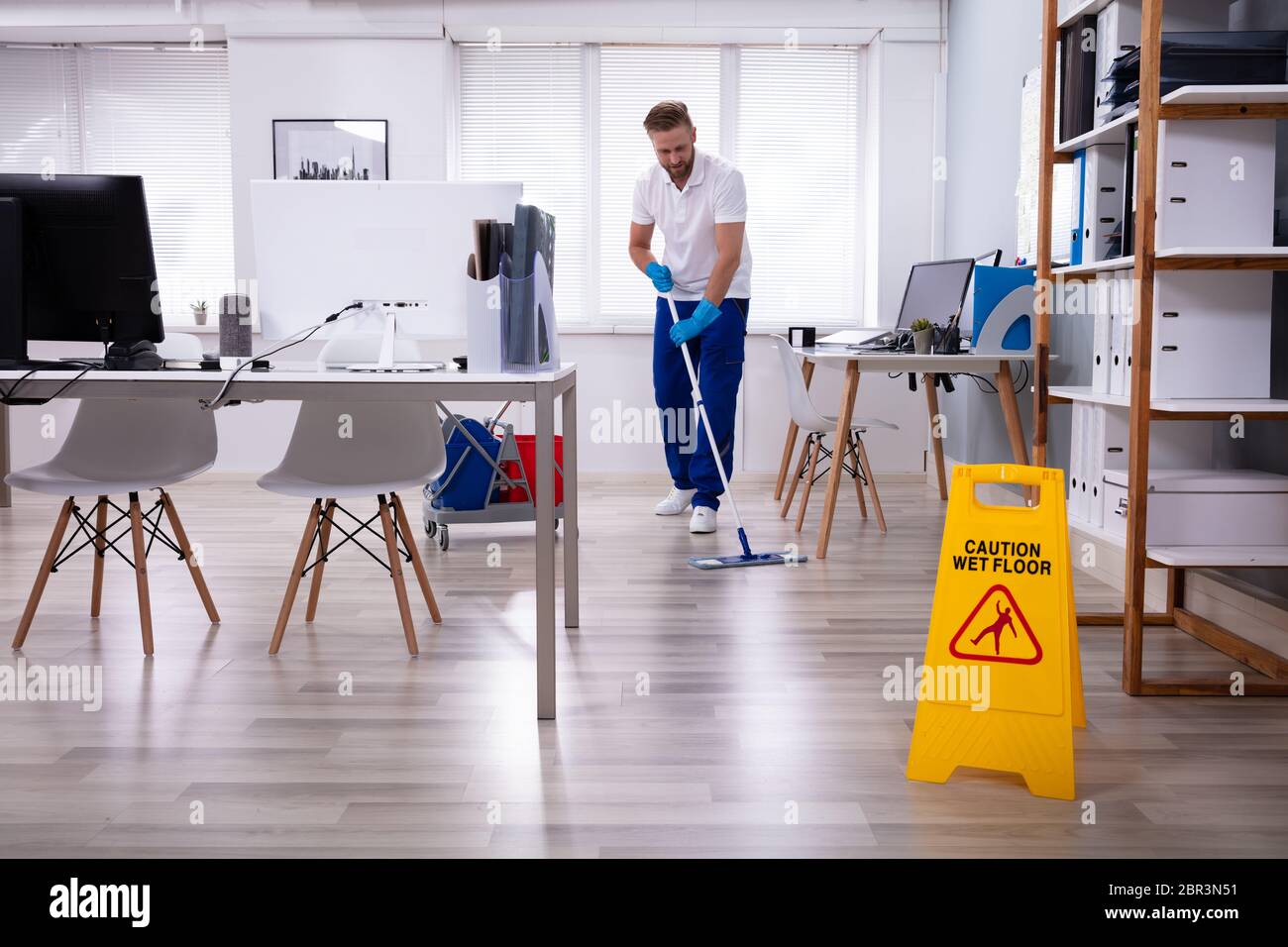Male janitor with mop cleaning modern office floor Stock Photo - Alamy