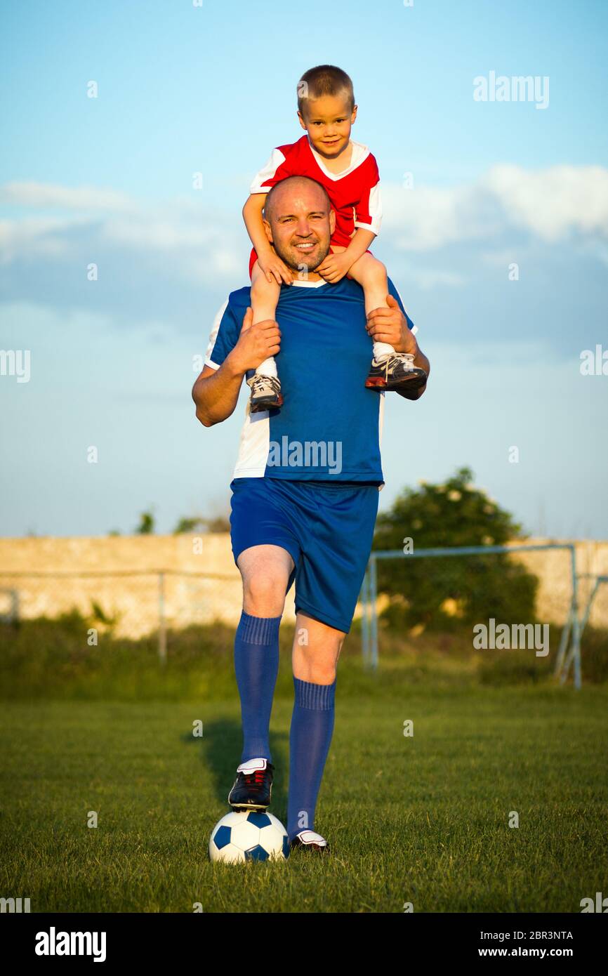 The happy family father and son is playing soccer outdoors on the green ...