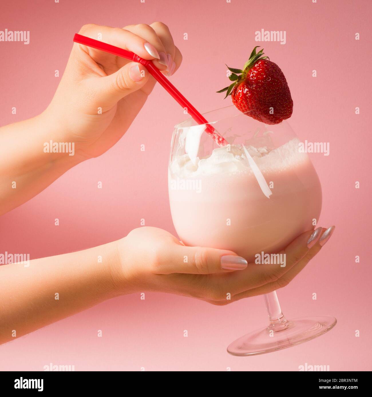 Female hands are holding strawberry milkshake drink with strawberry and ...