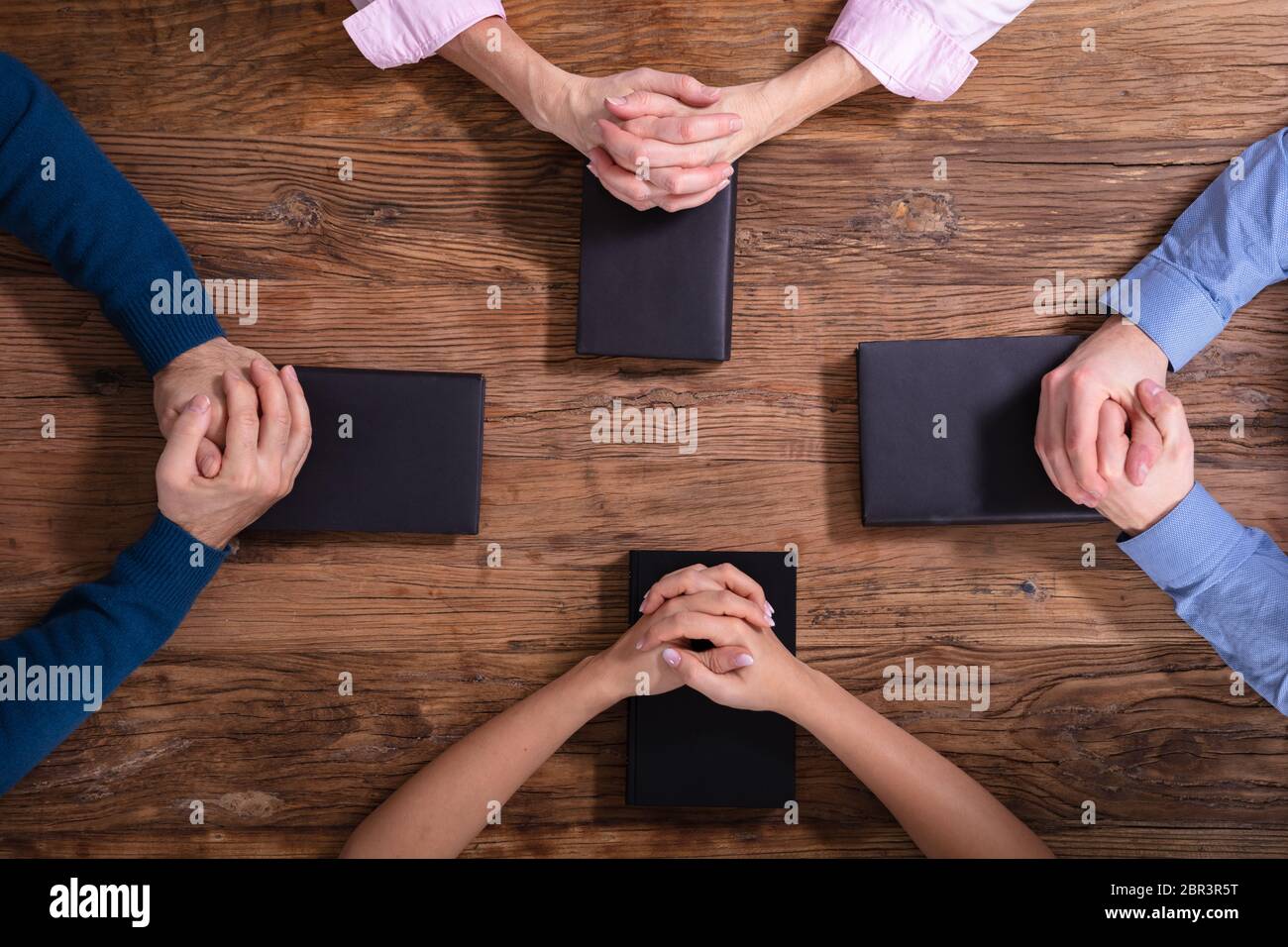 High Angle View Of People's Praying Hands On Holy Bible Stock Photo - Alamy