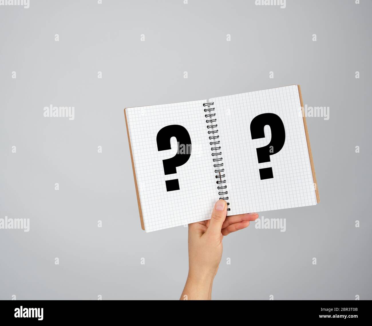 female hand holds open notepad into a cell on gray background, question ...