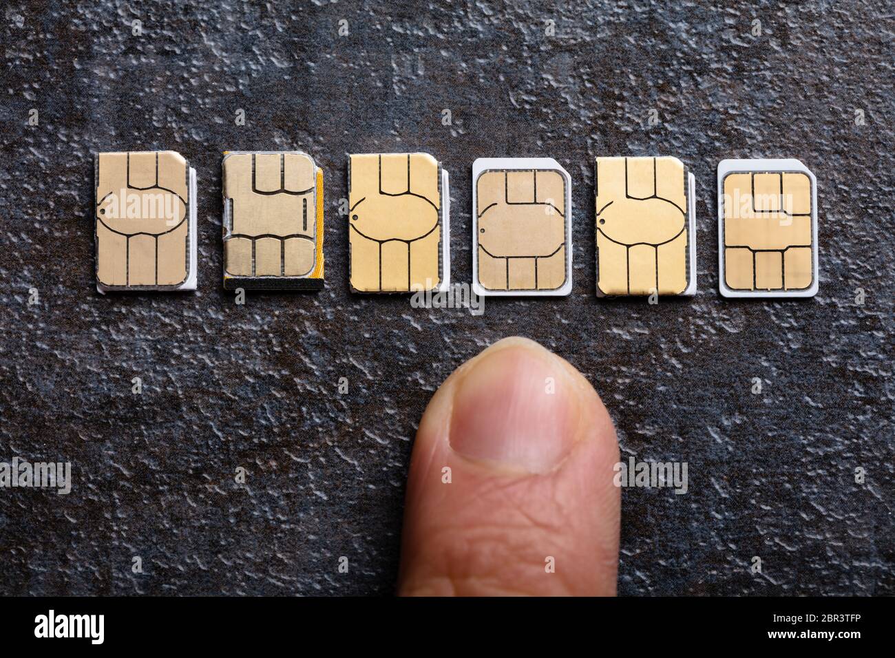 Person's Hand Selecting Sim Cards In A Row Over Concrete Black ...