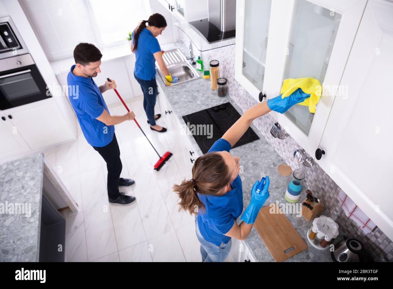 Group Of Young Janitors In Uniform Cleaning Kitchen At Home Stock Photo ...