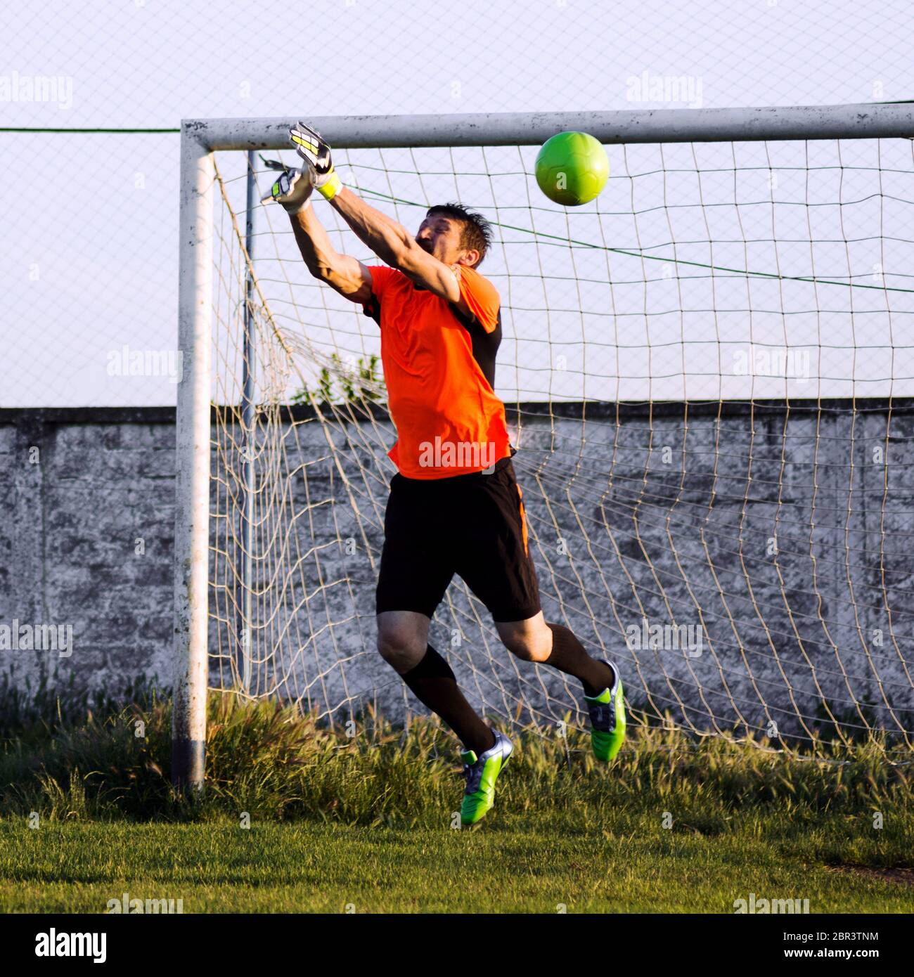 The goalkeeper or goalie is jumping to soccer ball on the playing field ...