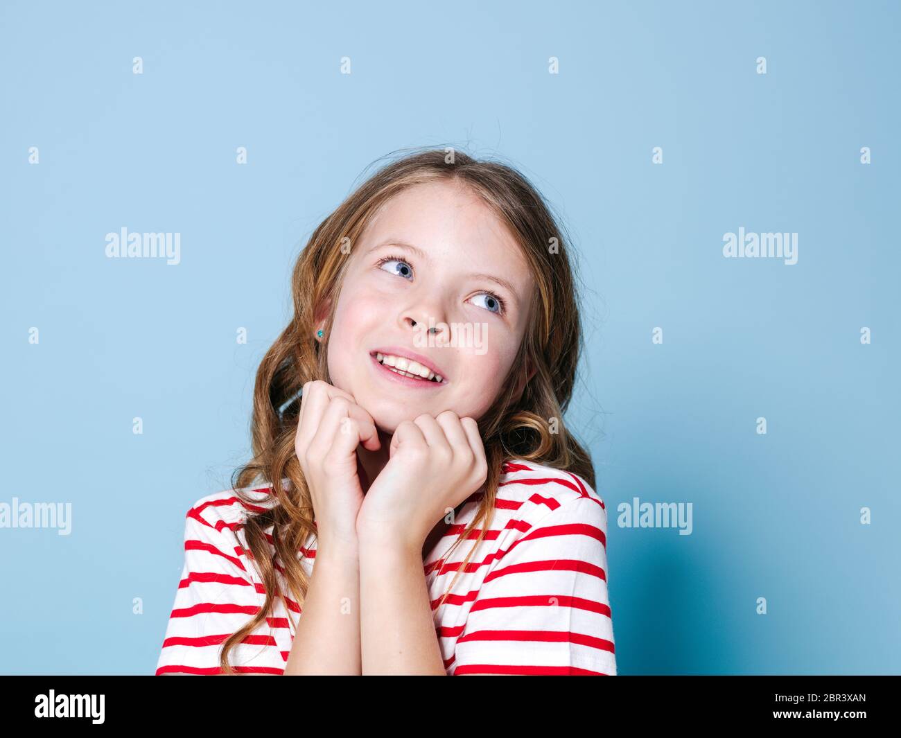 pretty girl with curly hair and red white striped shirt is posing in ...