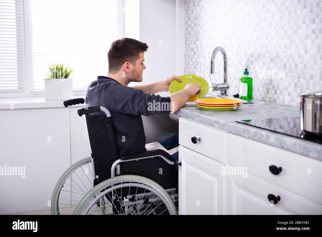 Handicapped Man Sitting On Wheelchair Washing And Cleaning Dishes In ...