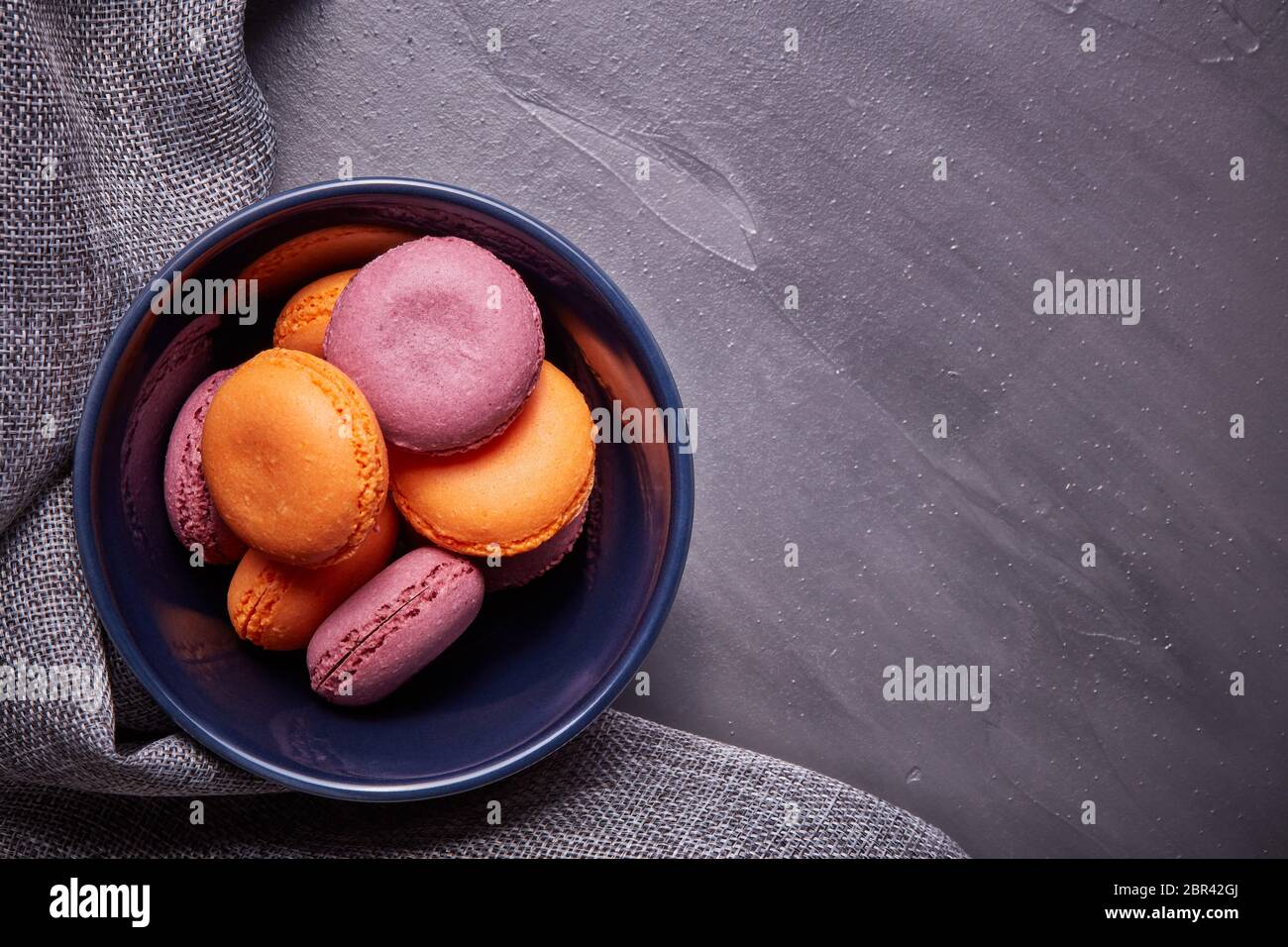 Bowl with delicious macaroons lying on gray background.Top view with ...