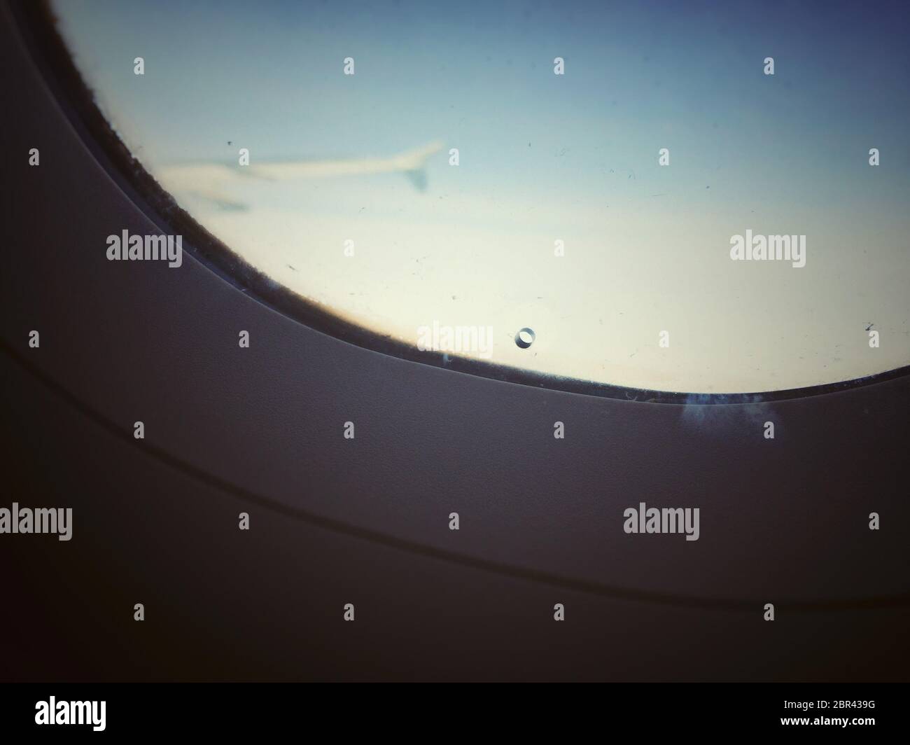Window of an airplane with a small hole to adjust the pressure between ...