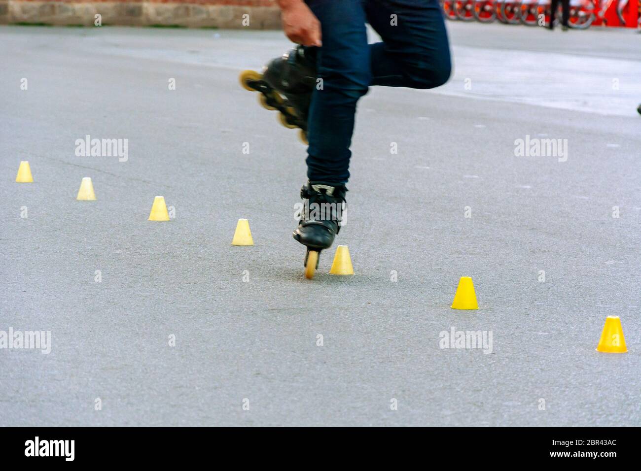 Feet of a skater while performing the slalom between yellow plastic ...