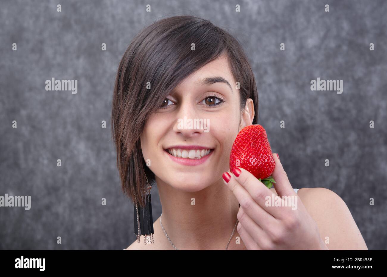 a pretty young brunette woman eating strawberry Stock Photo - Alamy