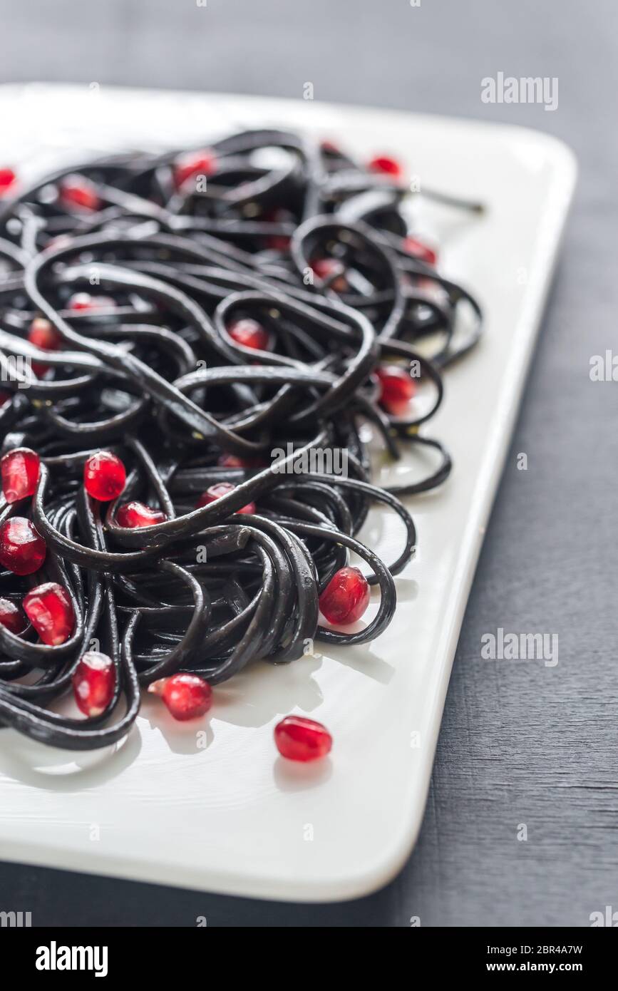 Black pasta with pomegranate seeds Stock Photo - Alamy