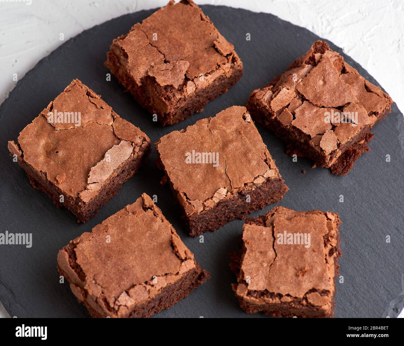 pieces of chocolate brownie on a black round graphite plate, top view ...