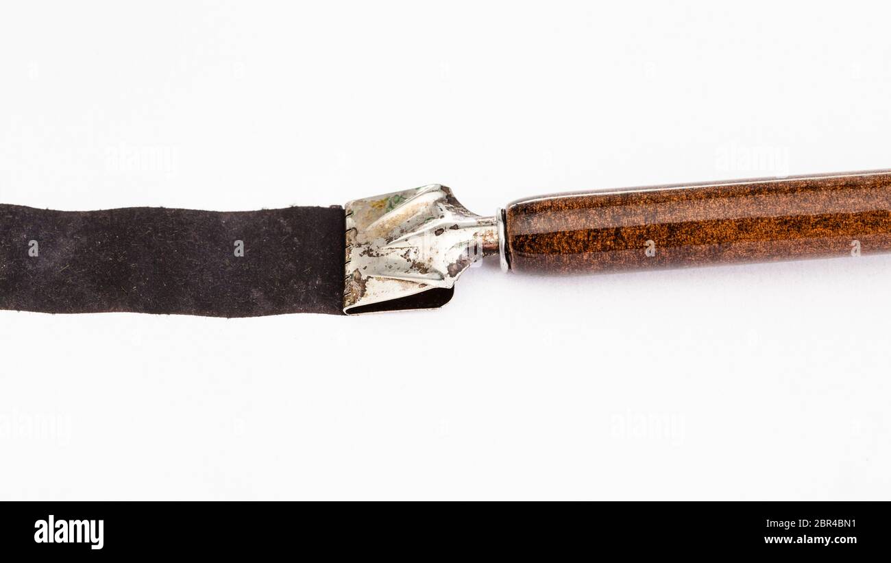 side view of brown wooden dip pen drawing black line on white paper by ...