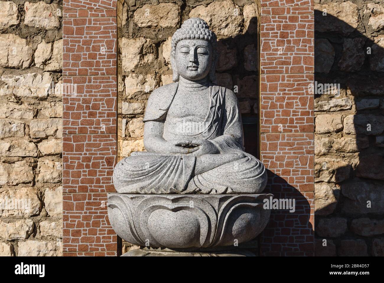 White stone statue of a Buddha on masonry background Stock Photo - Alamy